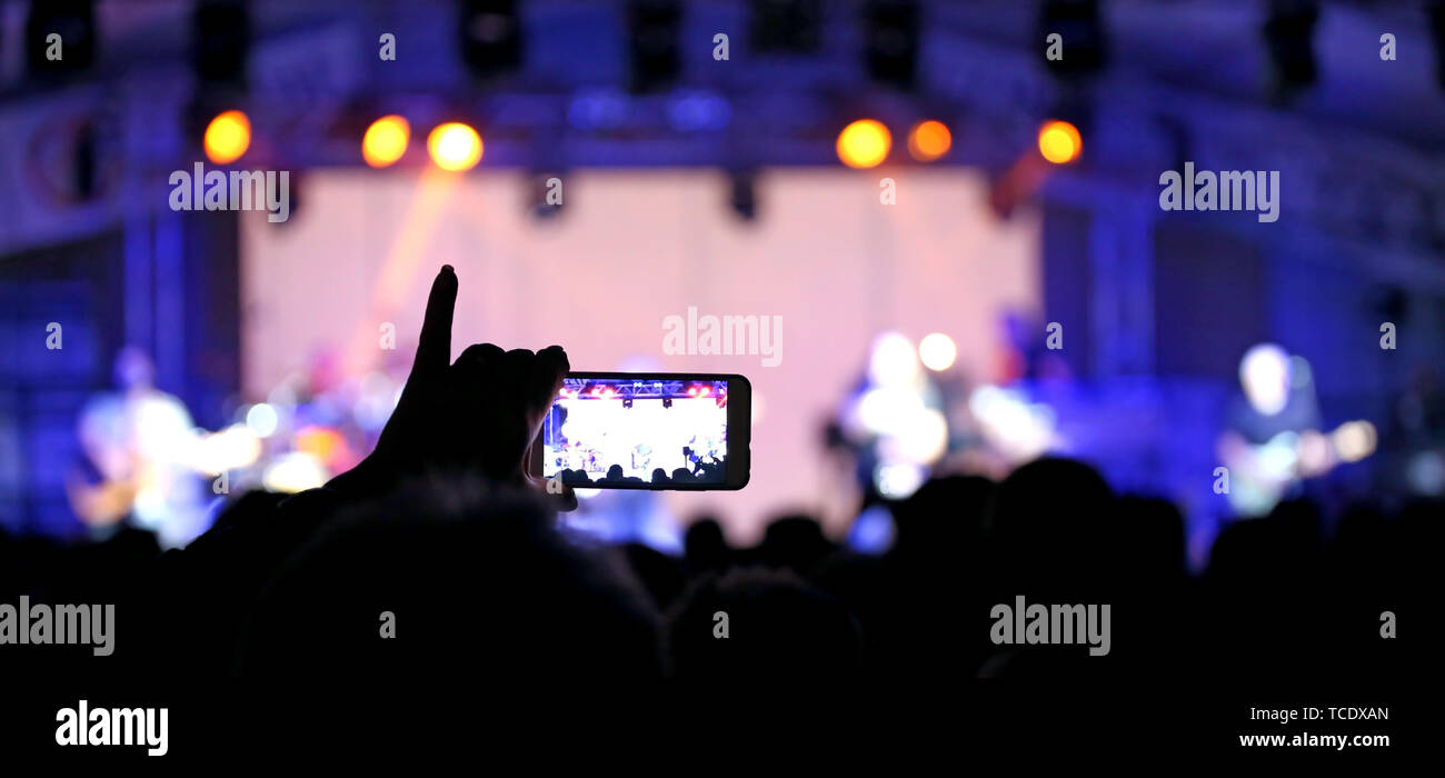 concert spectator photographs the band that performs on stage with his ...