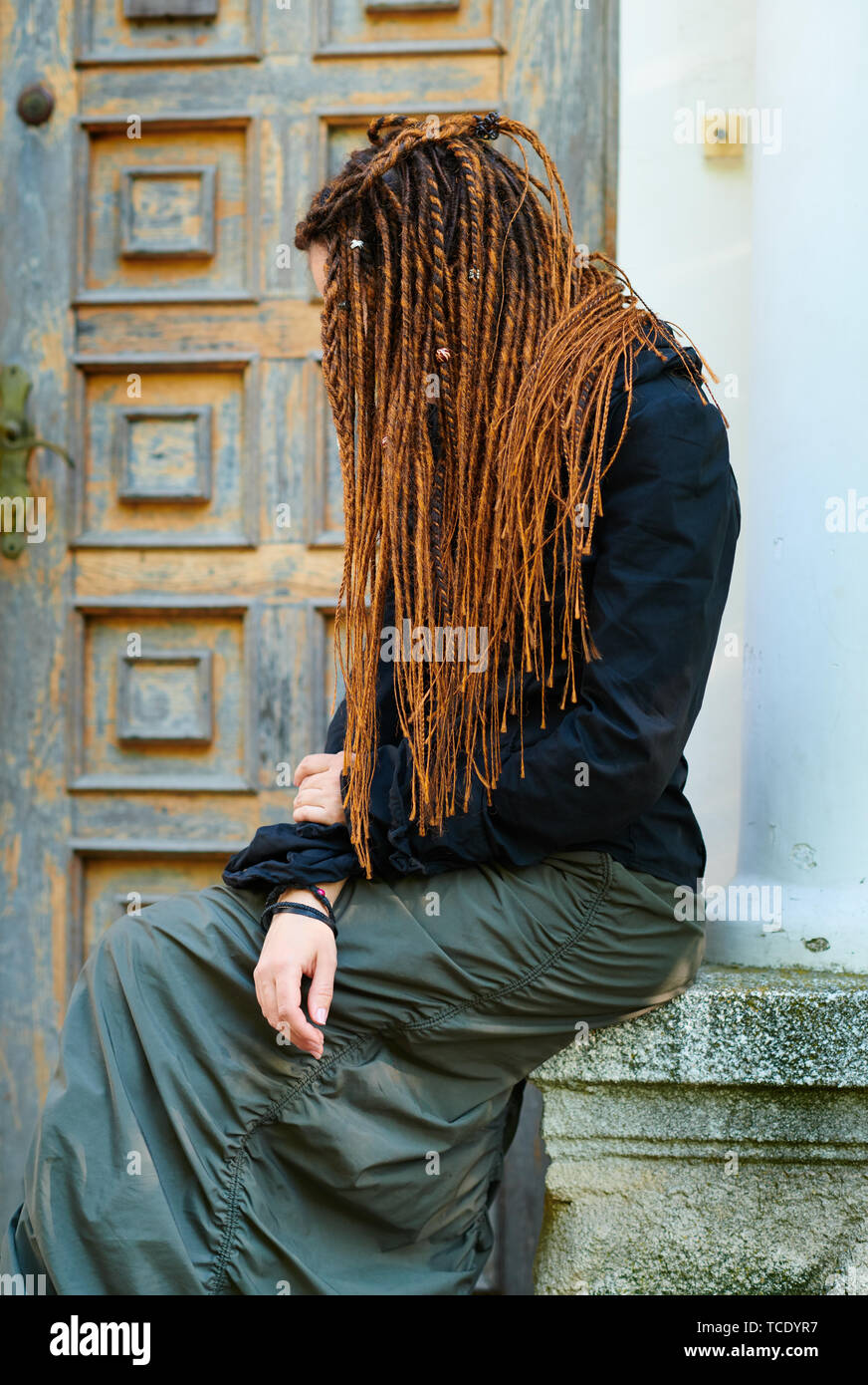 dreadlocks fashionable girl posing at old wooden door background. side ...