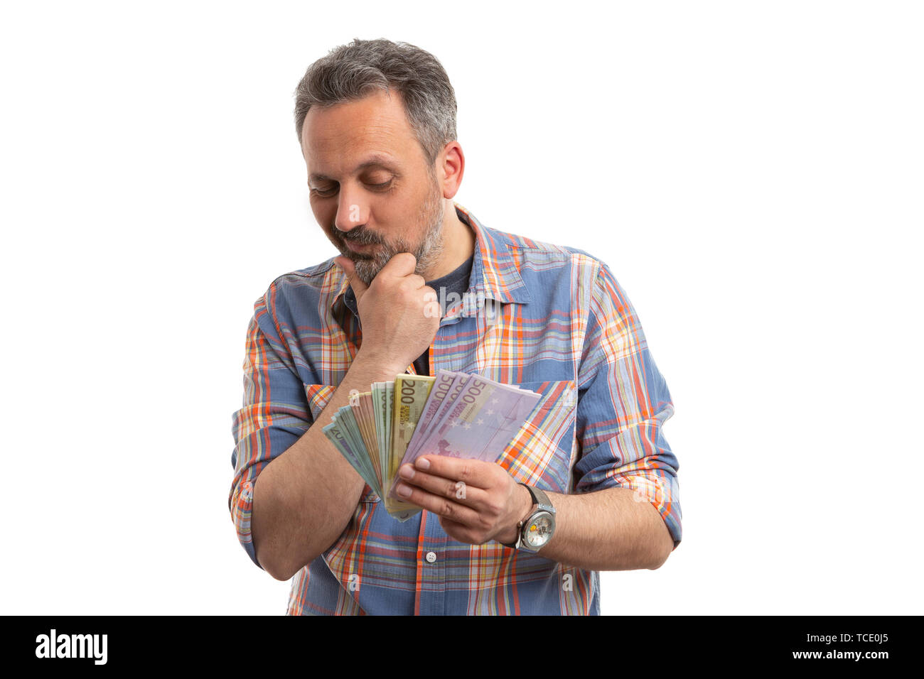 Man with curious expression looking at cash money in hand and counting ...