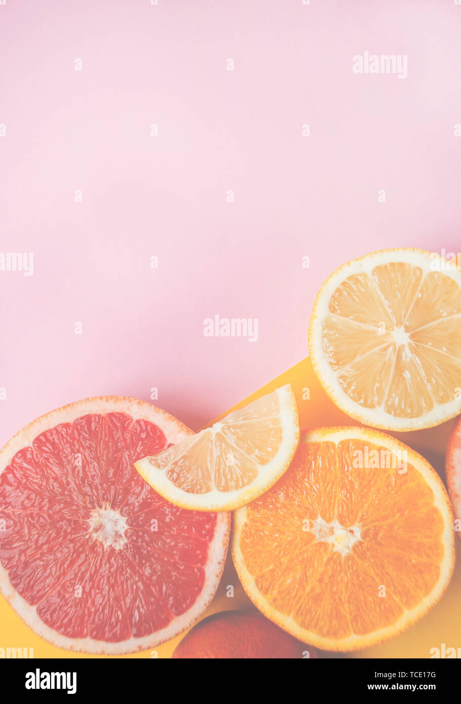 Flat lay of cut ripe juicy grapefruit, lemon and orange on pink ...