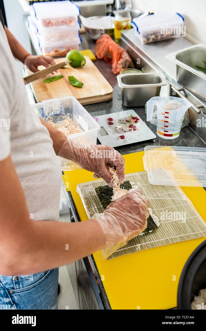 Hand of chef making Japanese sushi roll. Japanese chef at work prepares ...