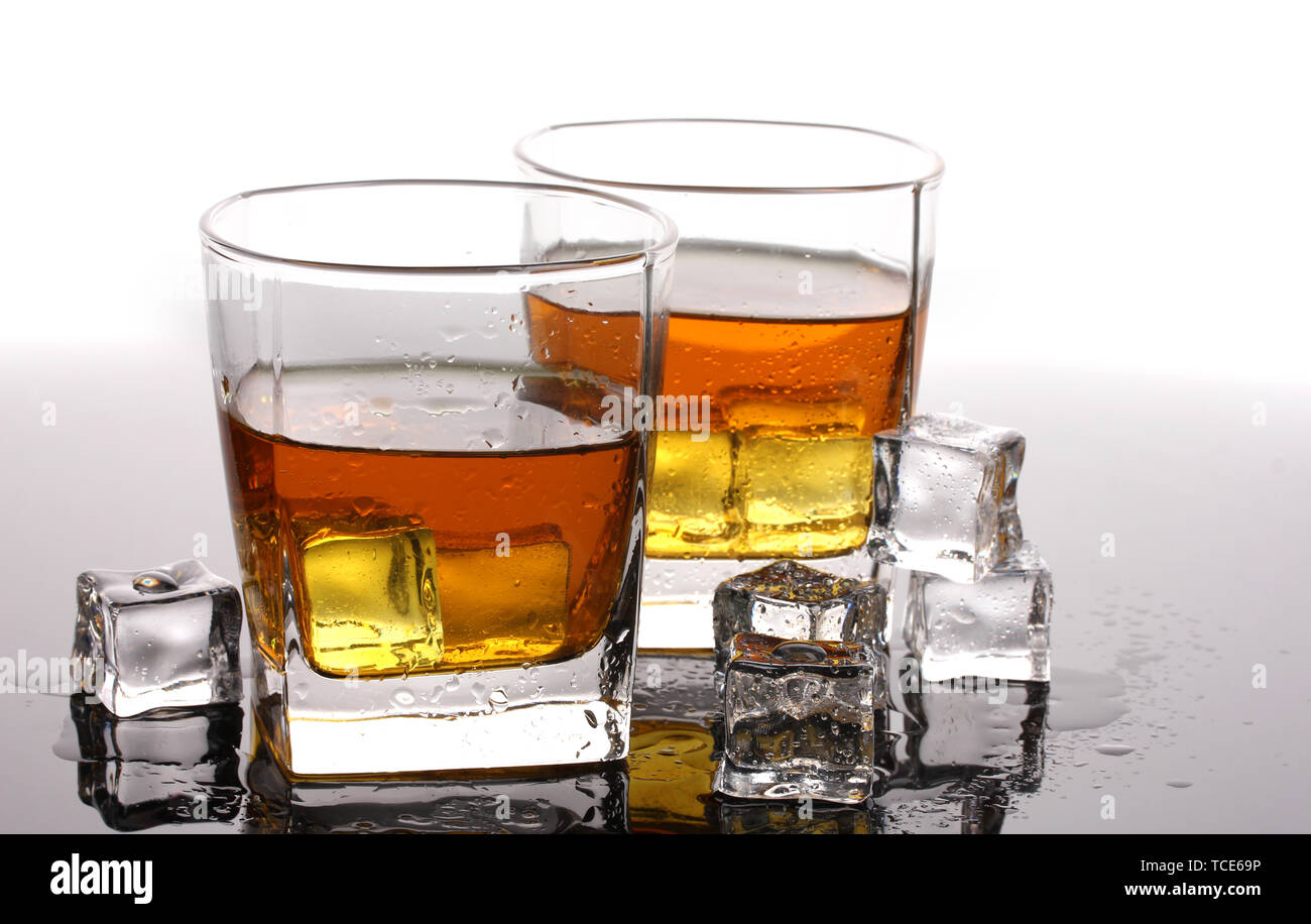 two glasses of scotch whiskey and ice on table isolated on white Stock ...