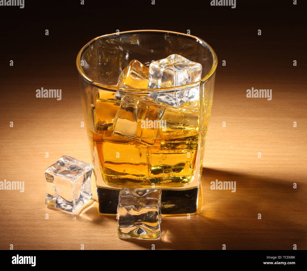 glass of scotch whiskey and ice on wooden table Stock Photo - Alamy