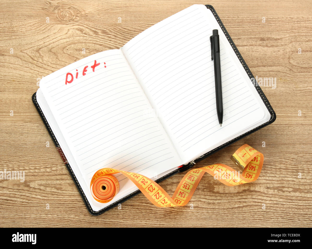 Planning of diet. Notebook measuring tape and pen on wooden table Stock ...