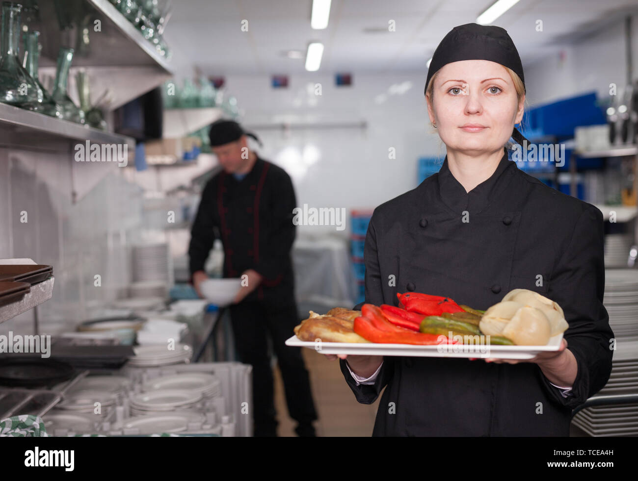 Proud woman cook standing in restaurant kitchen with finished dish ...