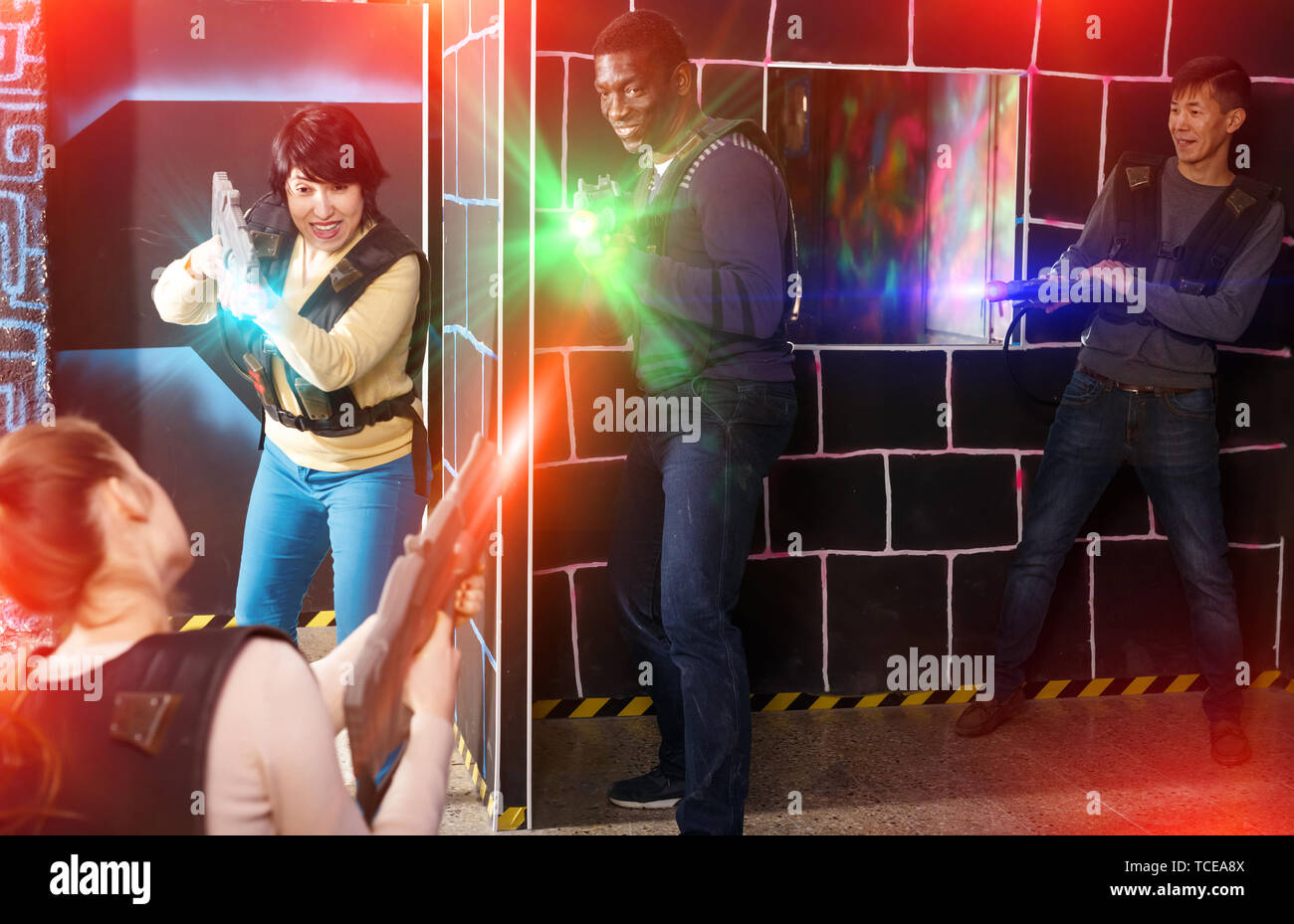 Happy international team aiming laser guns at other players during ...