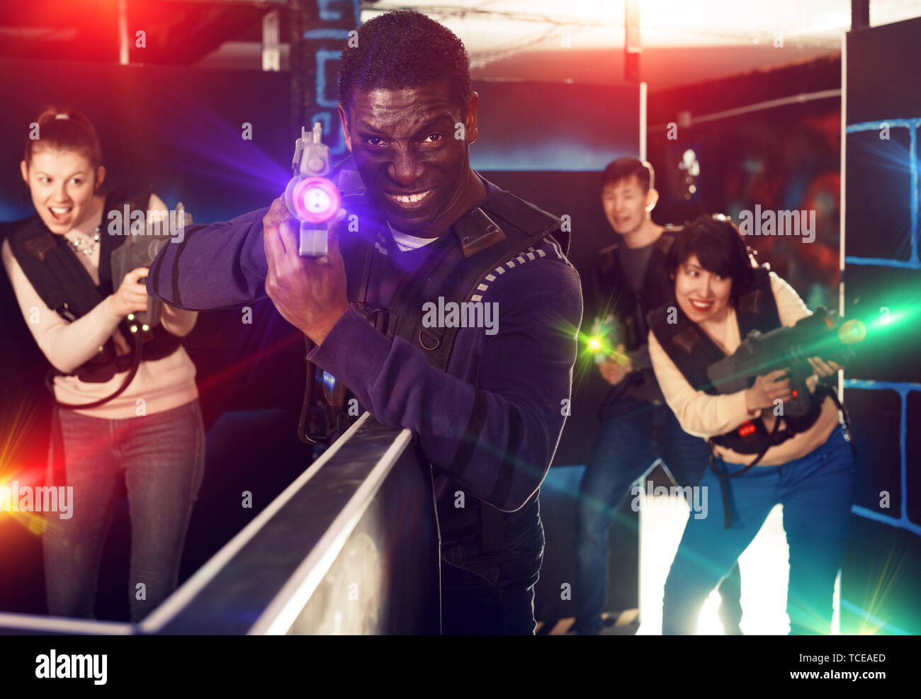 Emotional African American man aiming laser gun at other players during ...