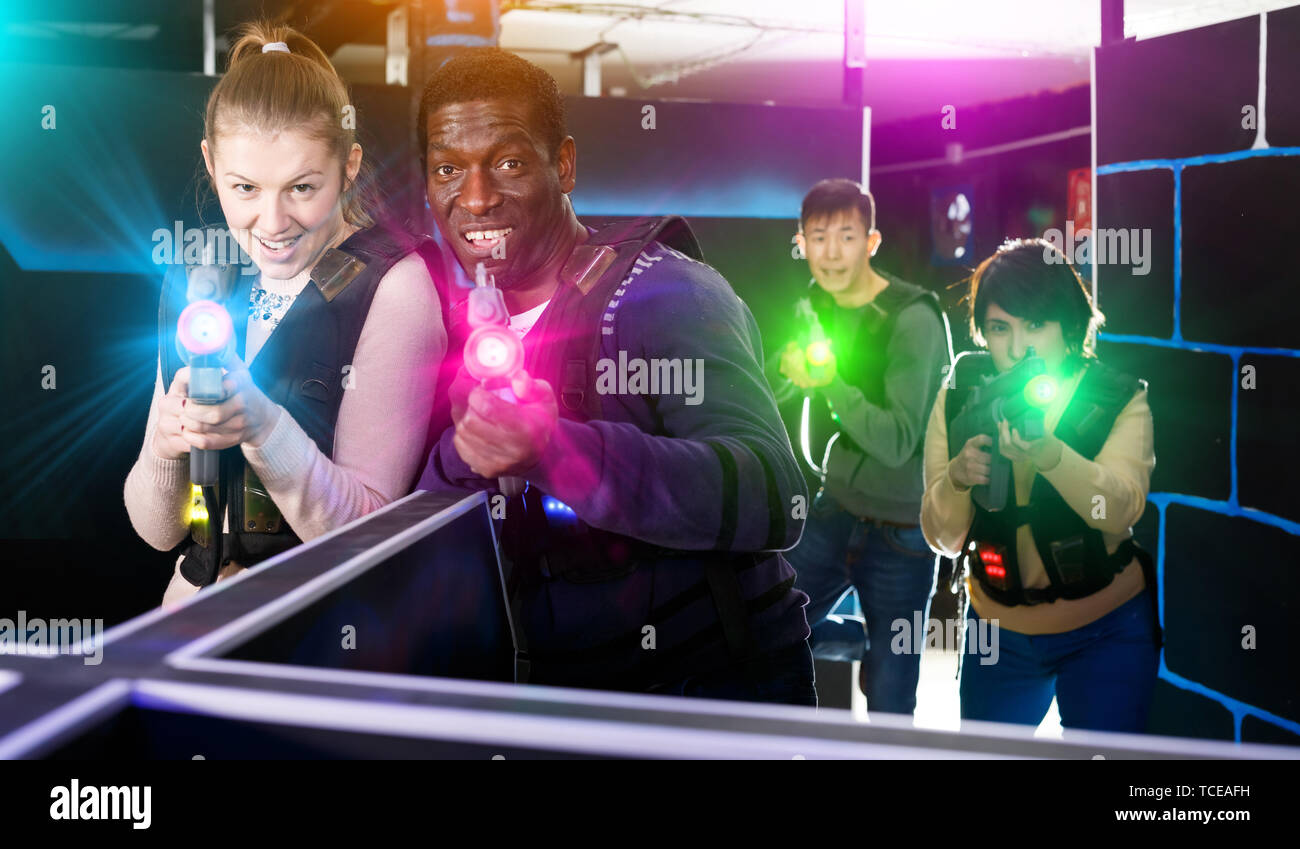 Fine laser tag players of different nationalities aiming laser guns at ...