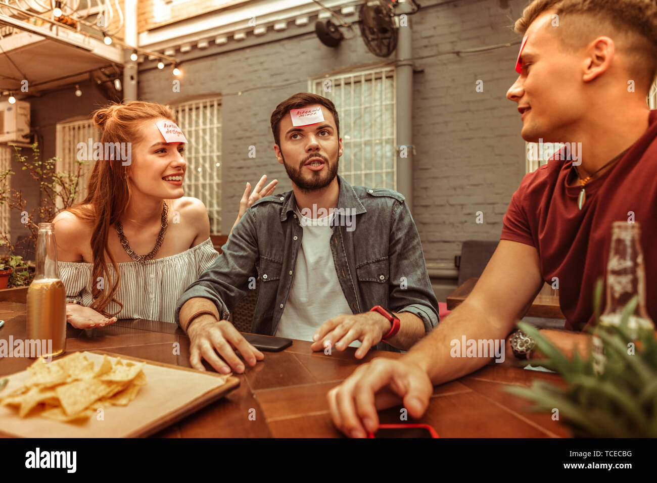 Friends playing in hedbanz. Contended vigorous young-adult joyous good ...