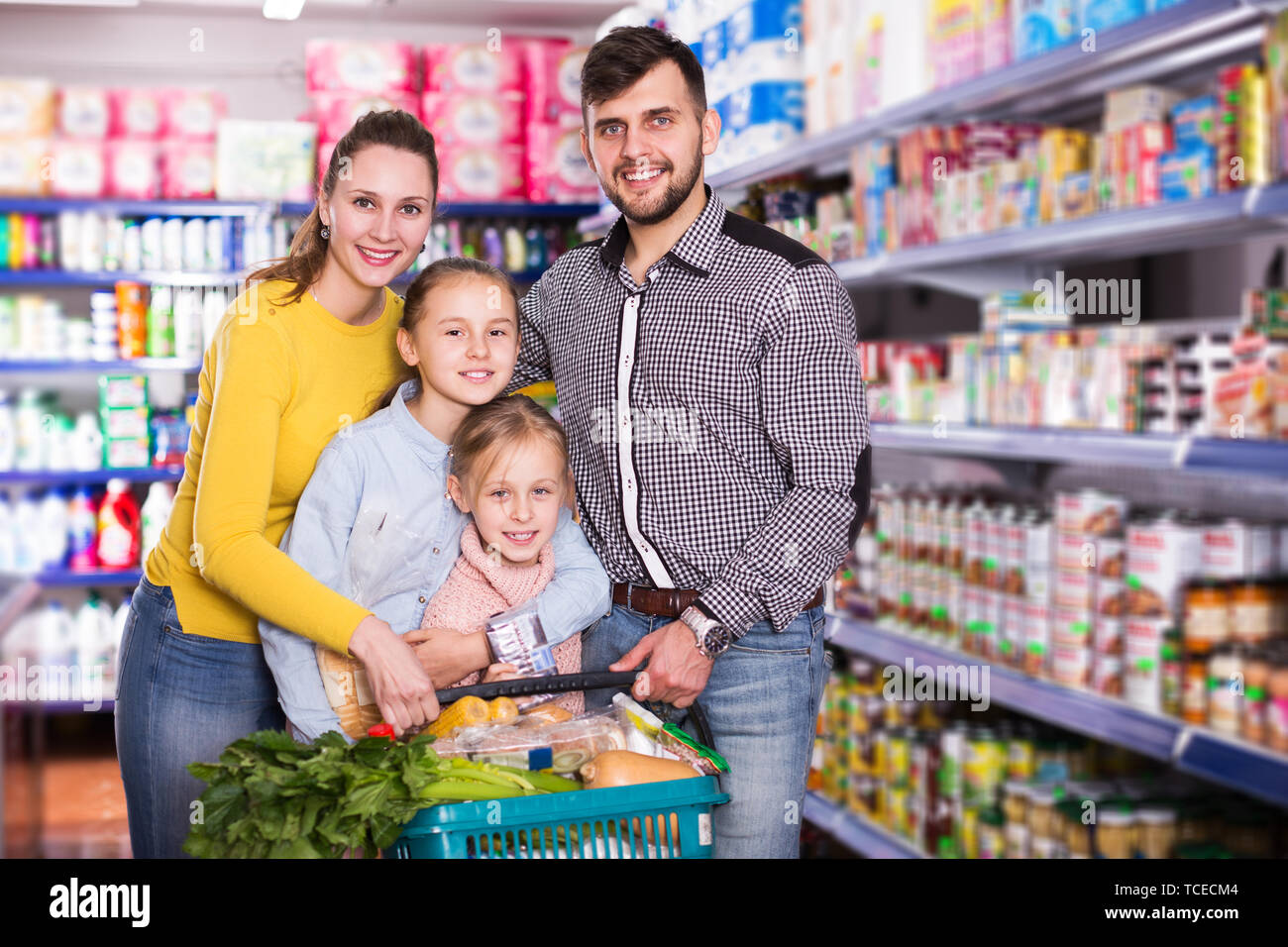 positive parents with two little girls with purchases during family ...