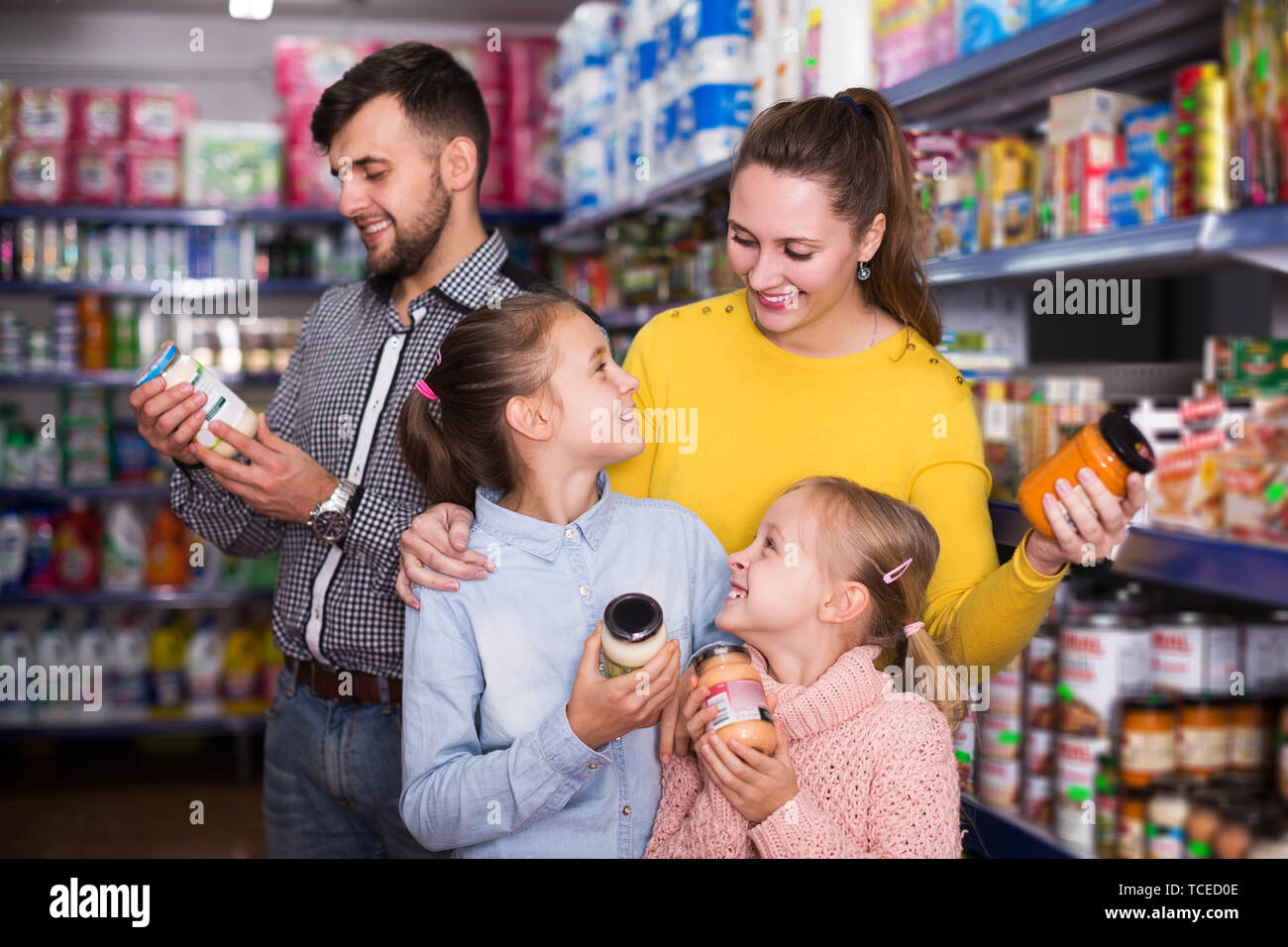 Young positive family of four shopping together in grocery store Stock ...