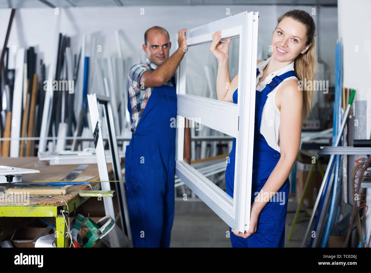 Portrait of two workers with plastic window frame in assembly shop ...