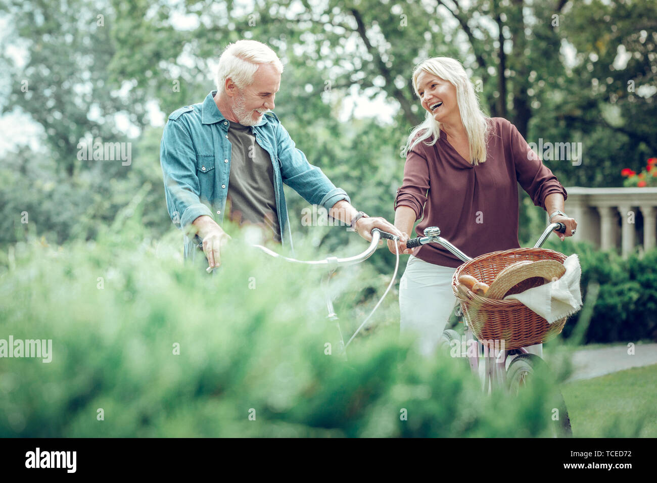 Pleasurable weekends. Delighted married couple riding bikes while ...