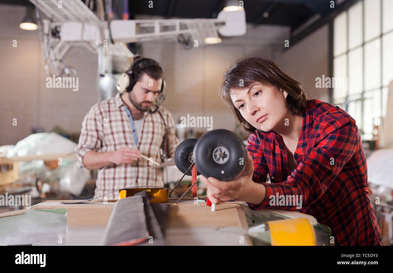Young woman enjoying her hobby - modeling light airplanes in aircraft ...