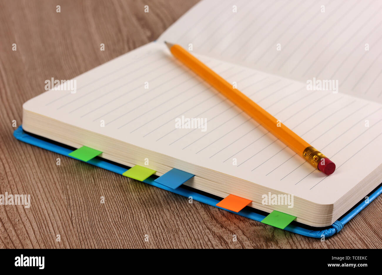 Open note book with stickies and pencil close-up on wooden background ...
