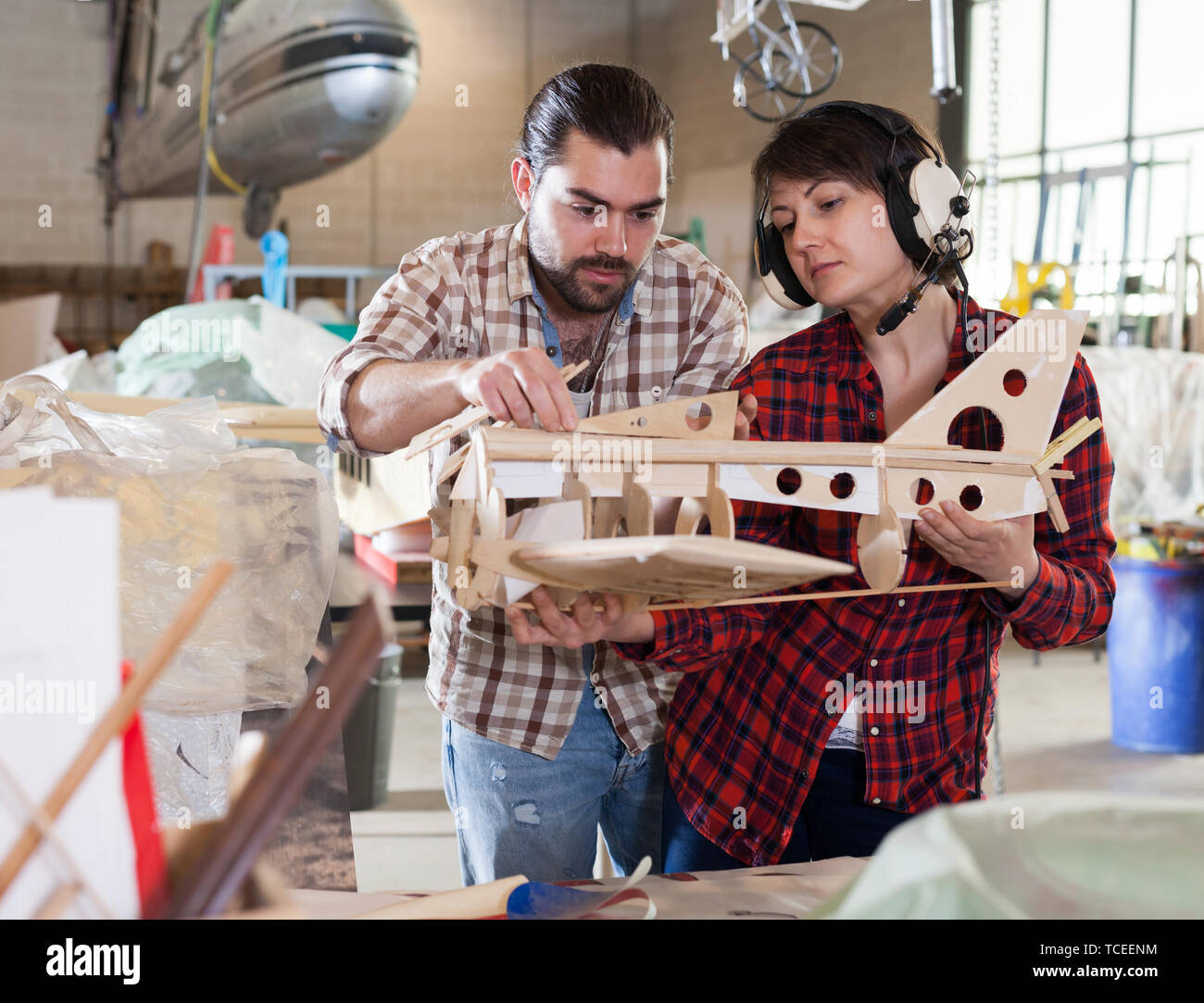 Female and male hobbyists engaged in creating plane models in aircraft ...