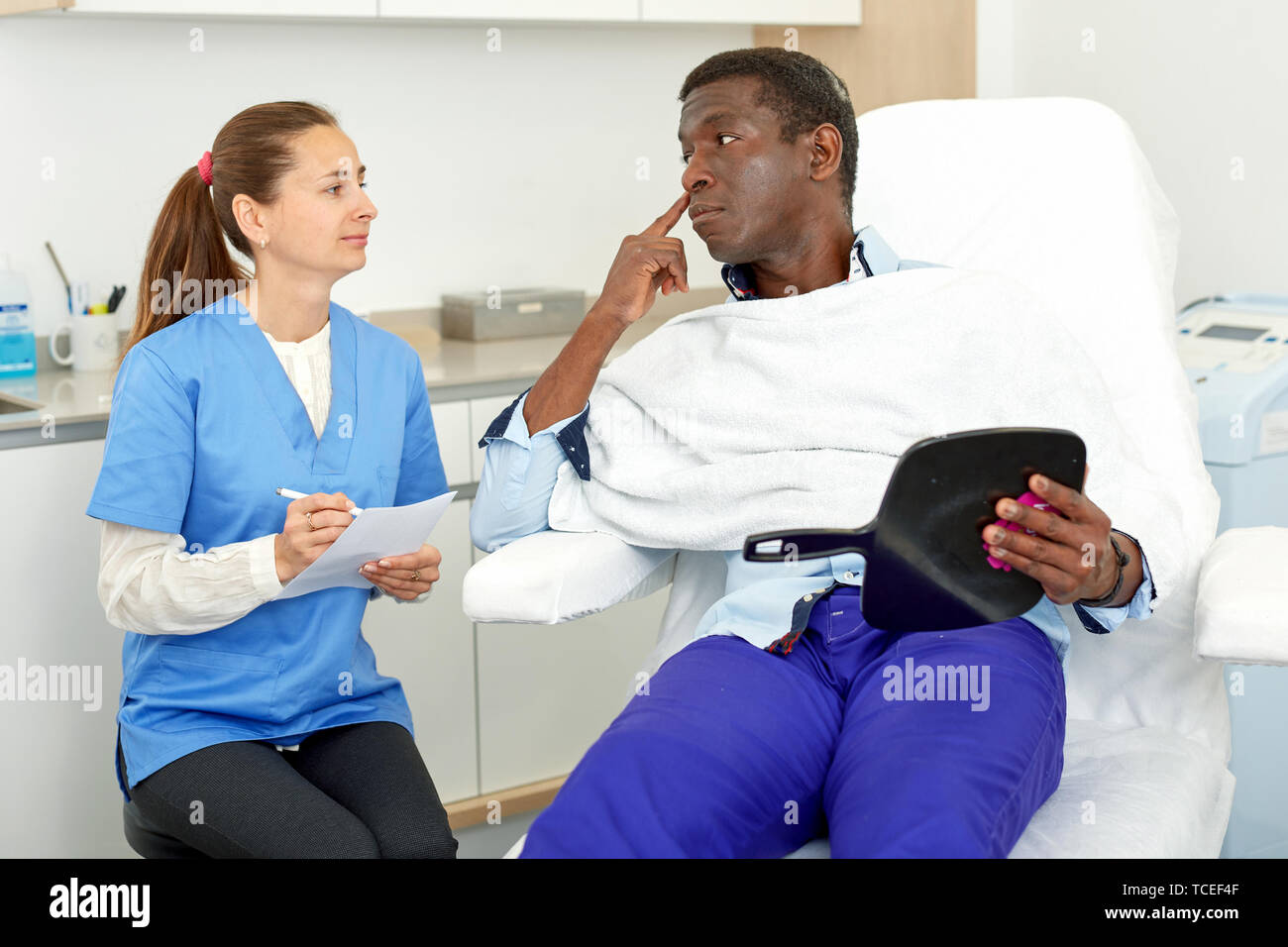 Male client with mirror having conversation with cosmetologist before ...