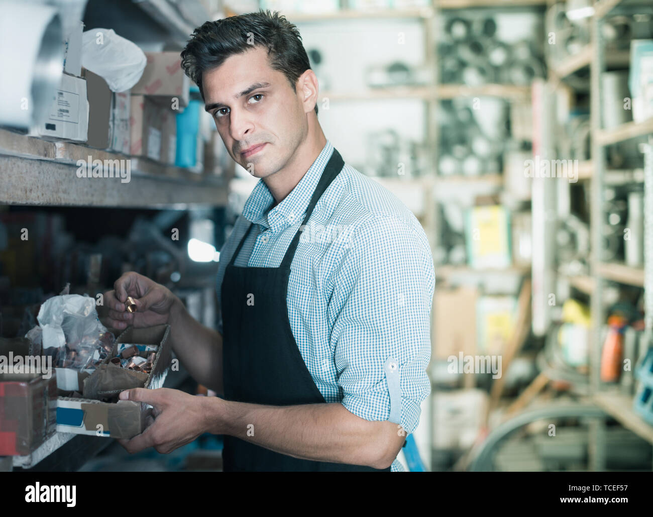 Adult foreman is checking small details which is in boxes in building ...