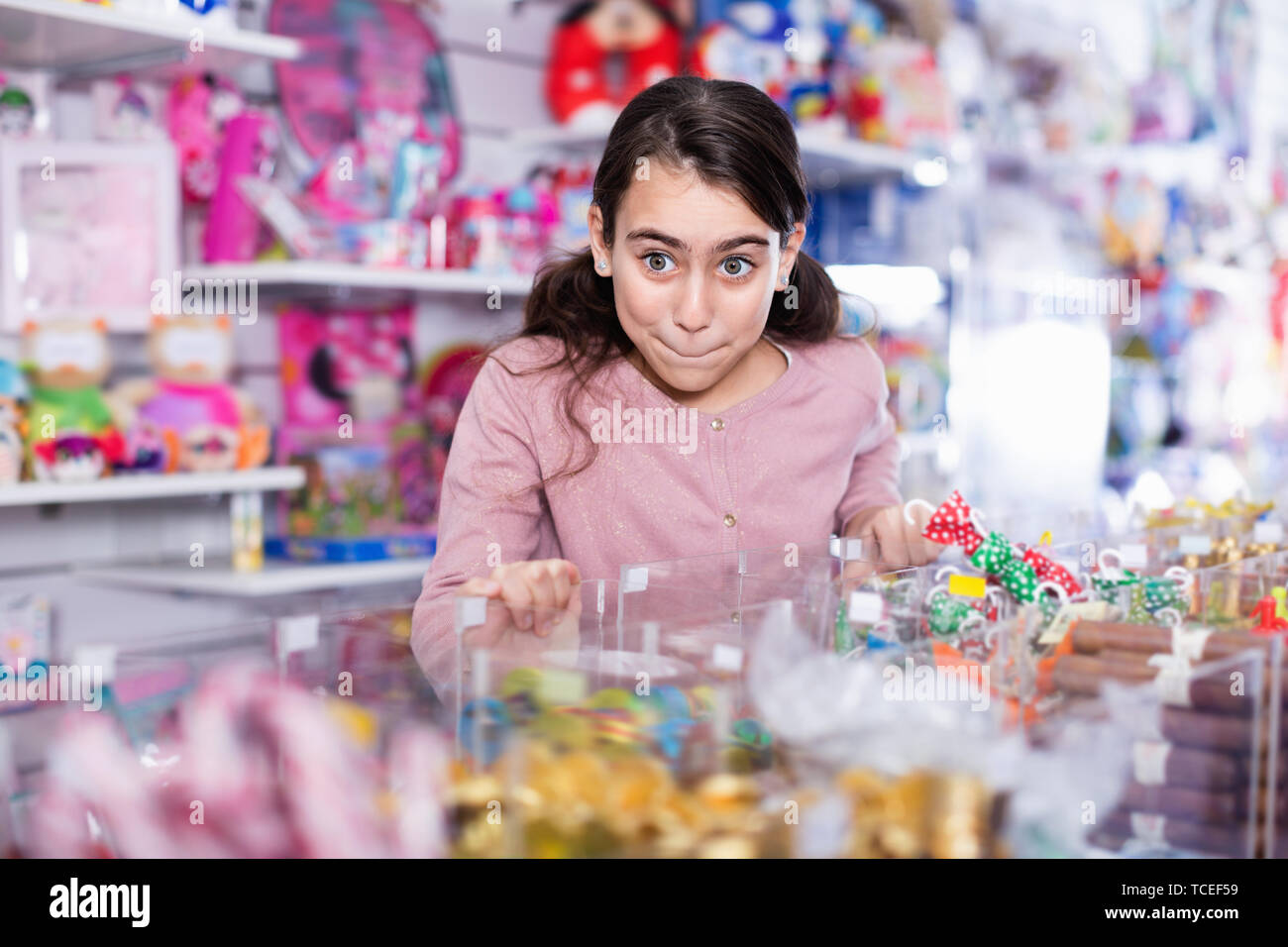 Emotional happy positive small girl choosing sweet candies in the candy ...