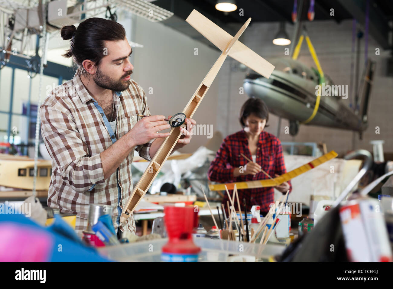 Young man amateur engaged in creating plane models in aircraft workshop ...