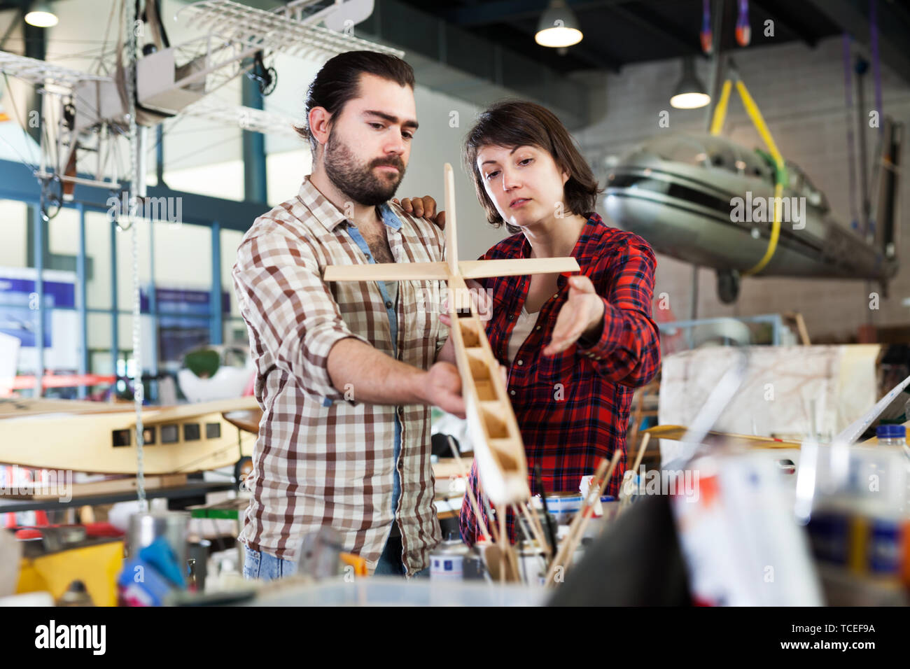 Female and male hobbyists engaged in creating plane models in aircraft ...