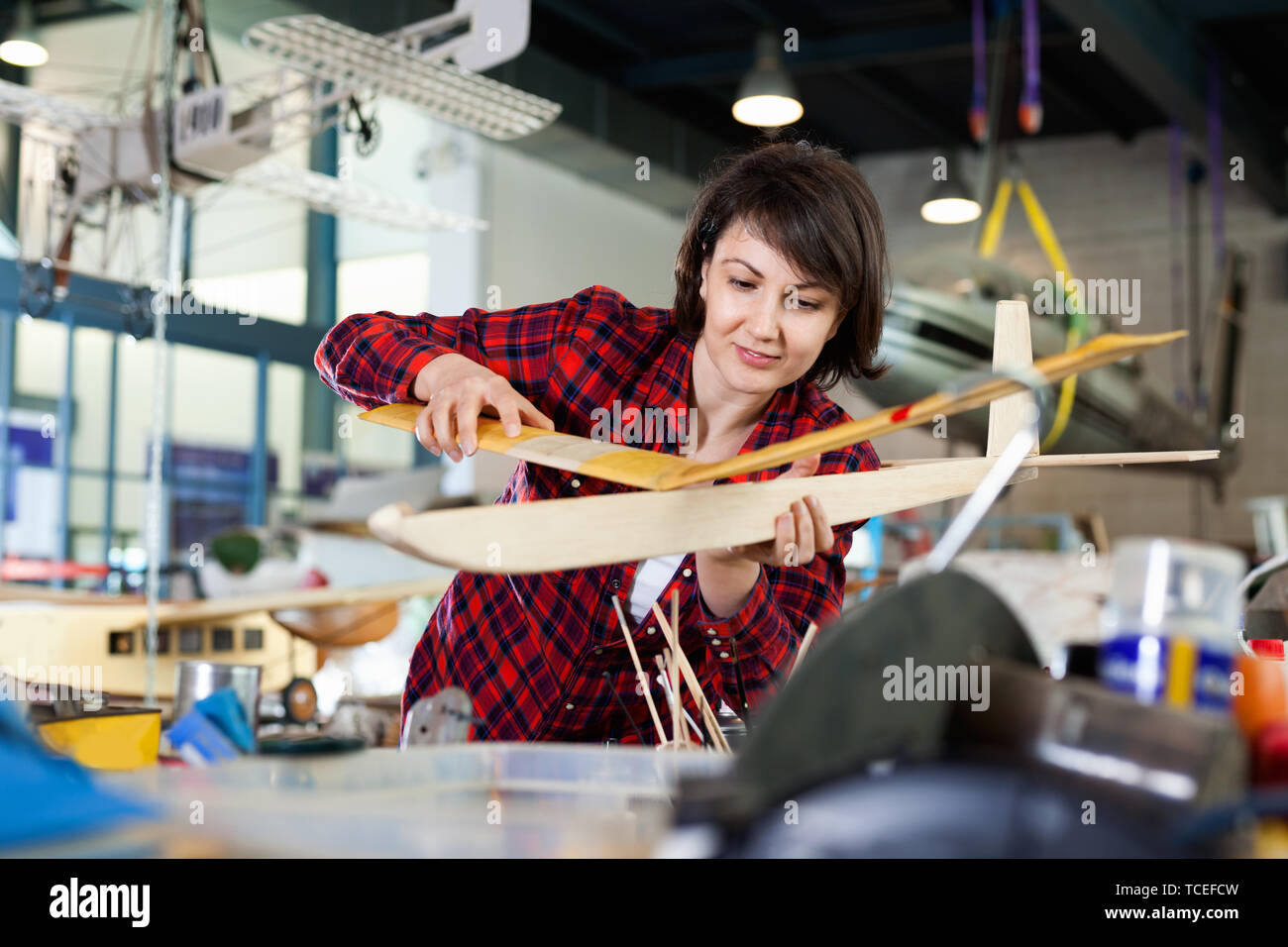 Happy positive smiling female aircraft enthusiast engaged in creating ...