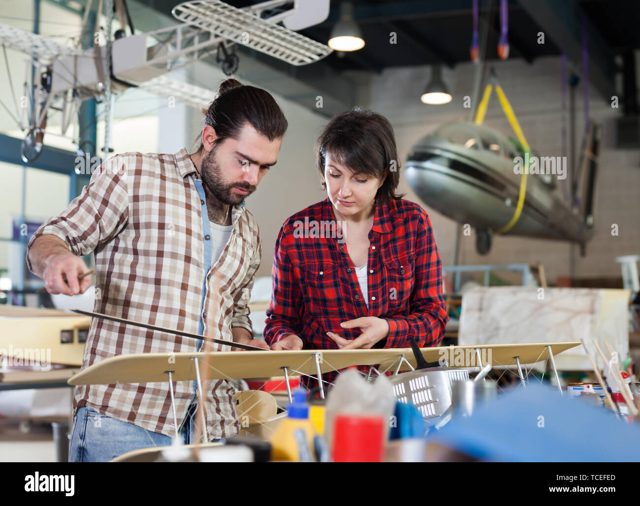 Portrait of cheerful female and male hobbyists with plane models ...
