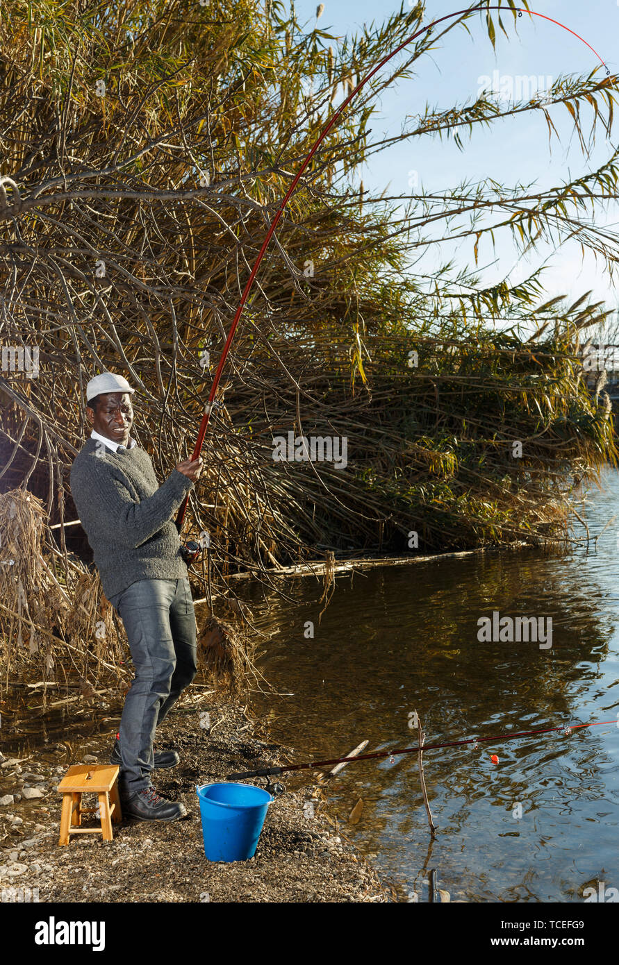 Portrait of afro fisherman standing near river and pulling fish Stock ...