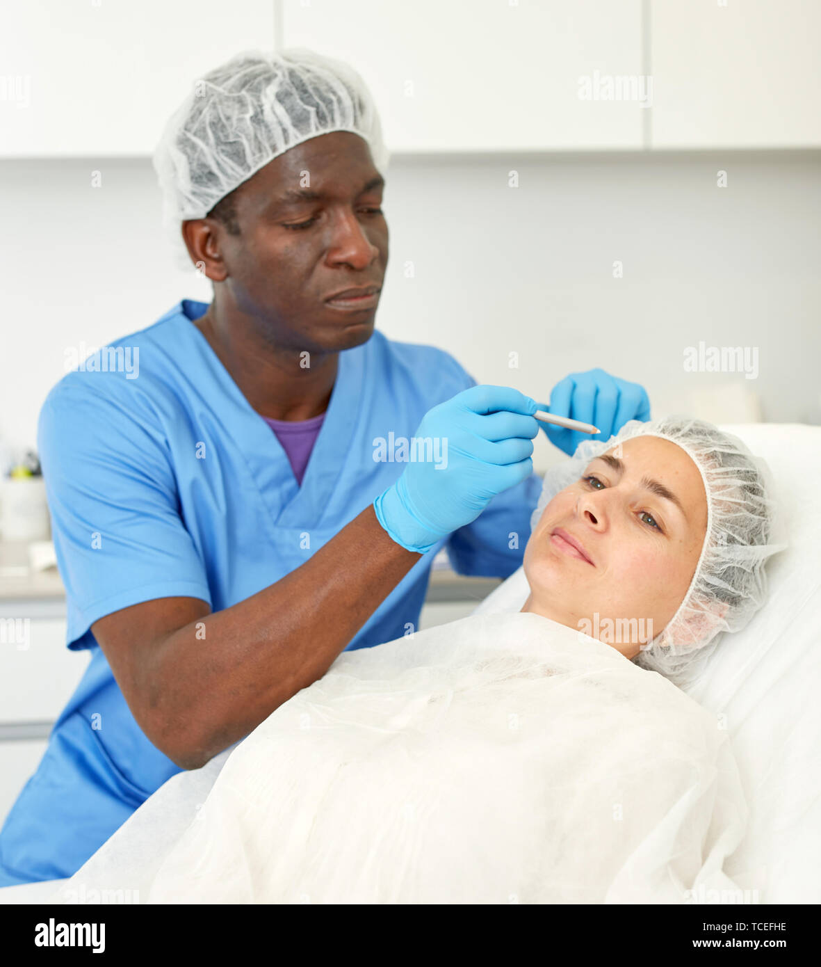 Cosmetician male is preparing client for mesotherapy in modern beauty ...