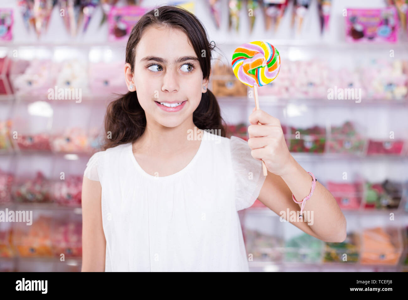 Girl standing with sweet colored lolly on stick in candy shop Stock ...