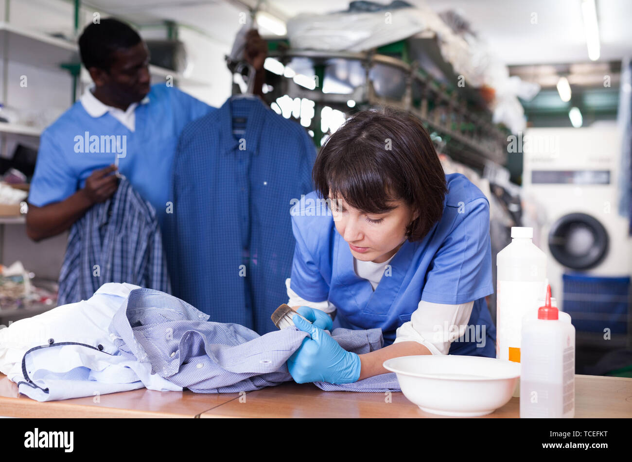 Focused young woman dry cleaning clothes in laundry Stock Photo - Alamy