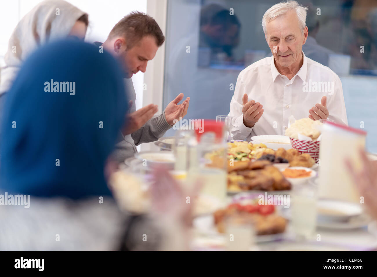 modern muslim family praying before having iftar dinner together during ...