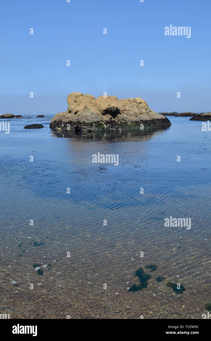 Low tide calm seas reveals a large rock in the ocean Stock Photo - Alamy