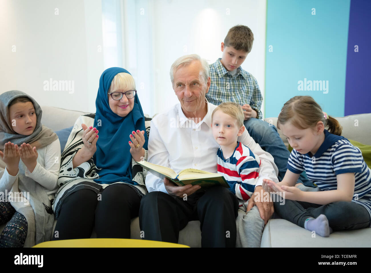 modern muslim family grandparents with grandchildren reading Quran and ...