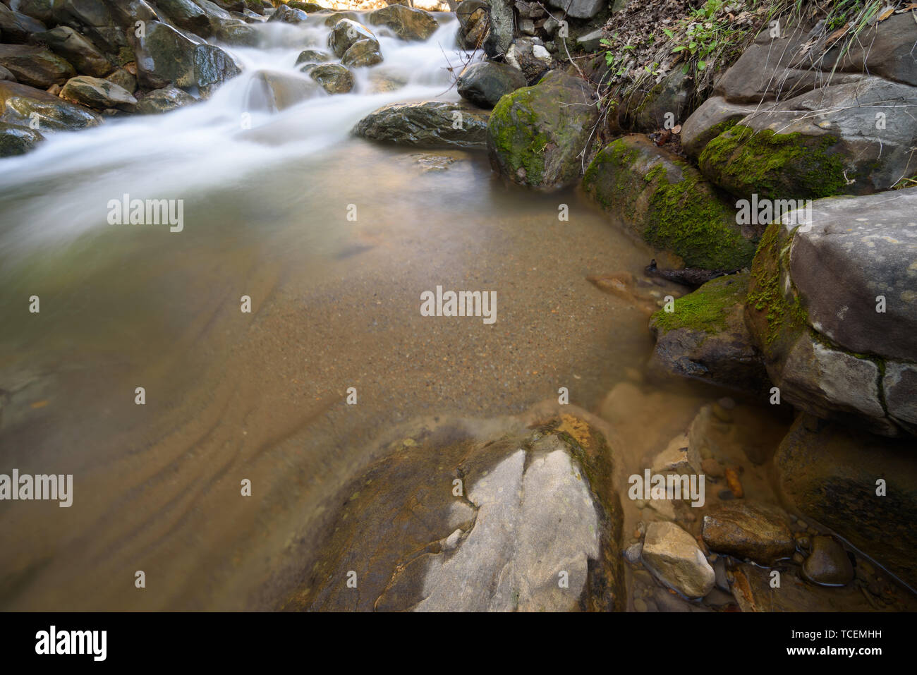 Fast moving water flowing over sand and rocks Stock Photo - Alamy