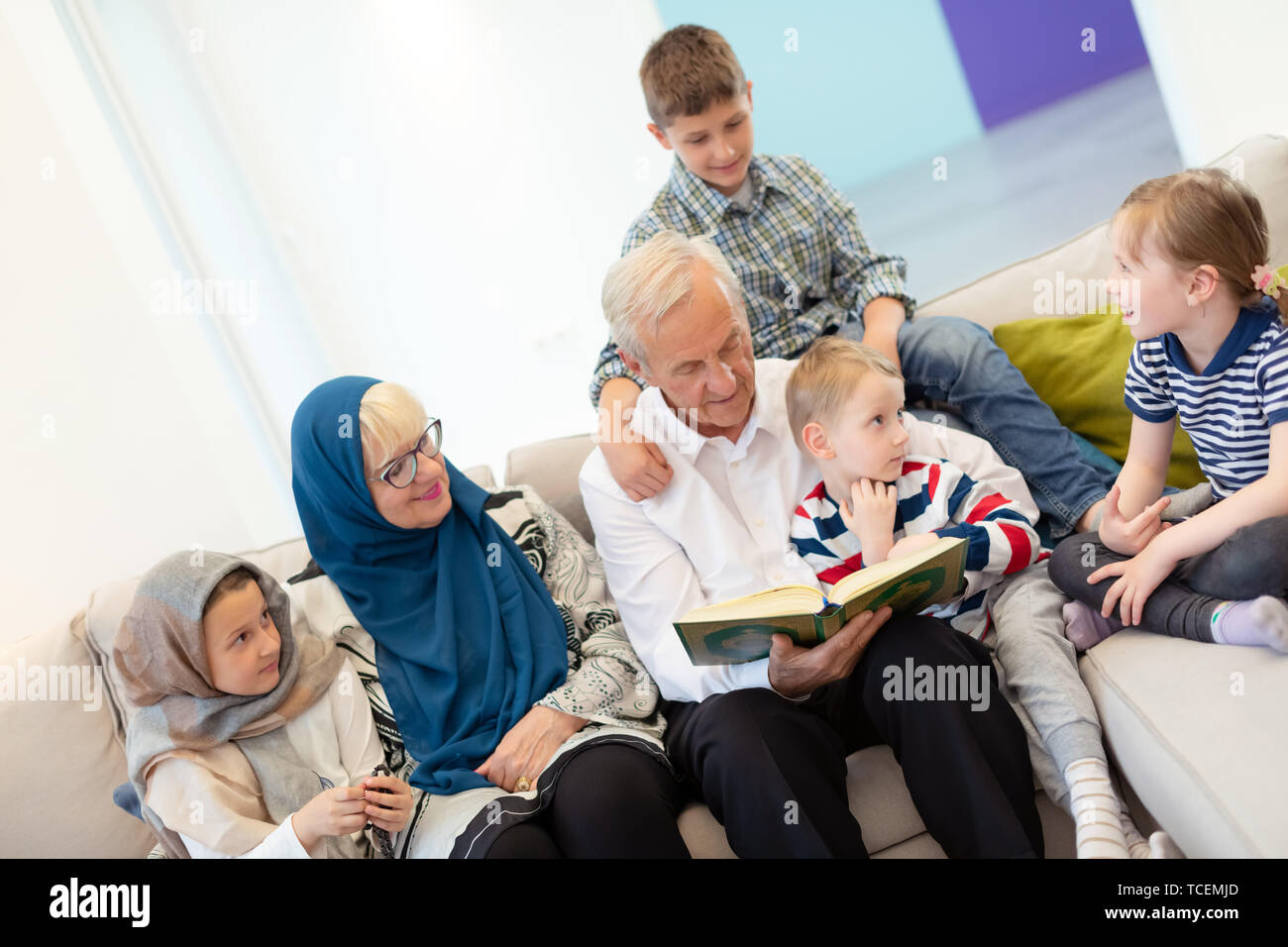modern muslim family grandparents with grandchildren reading Quran and ...