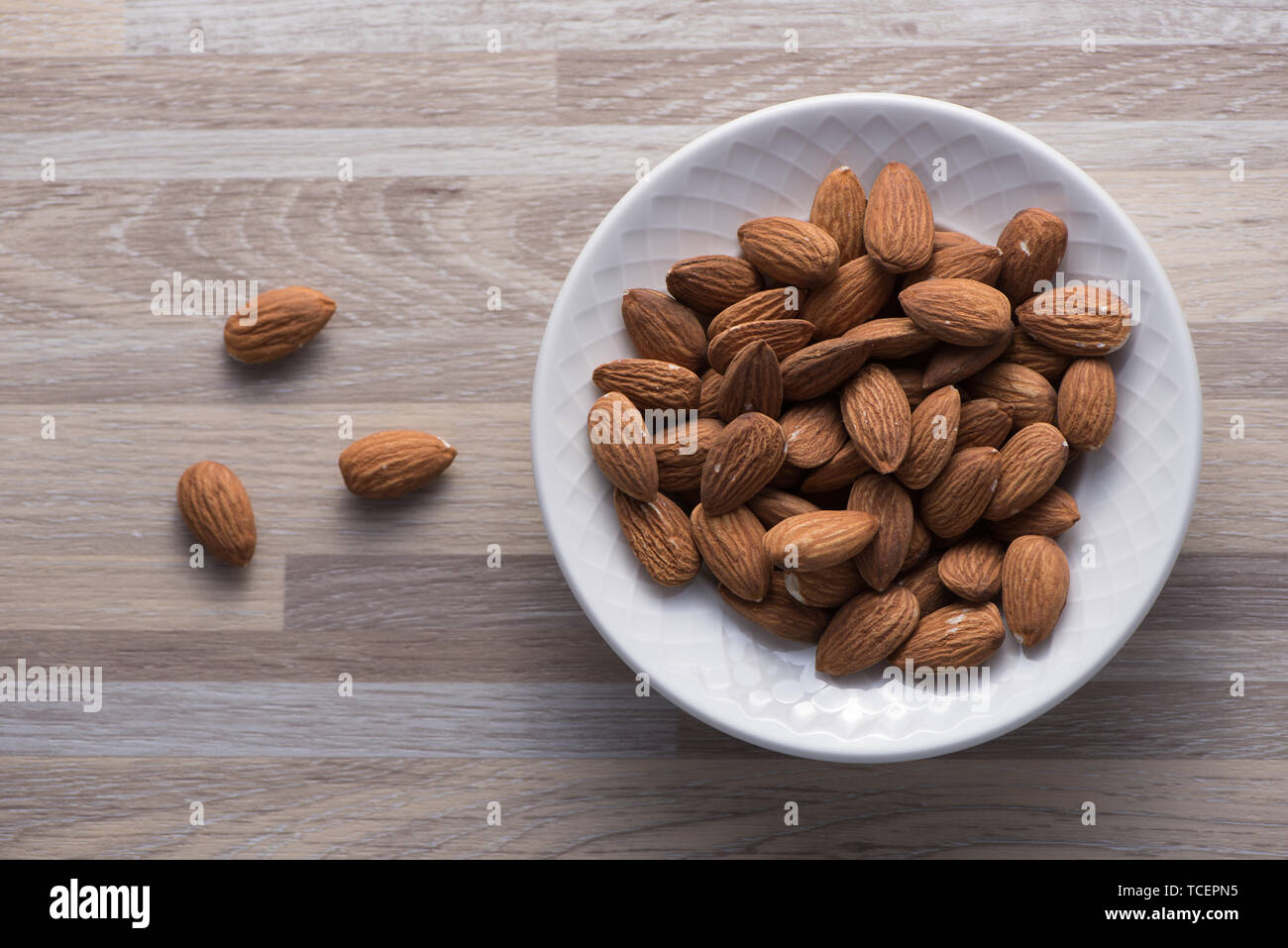 White bowl of whole raw almonds rustic wood surface Stock Photo - Alamy