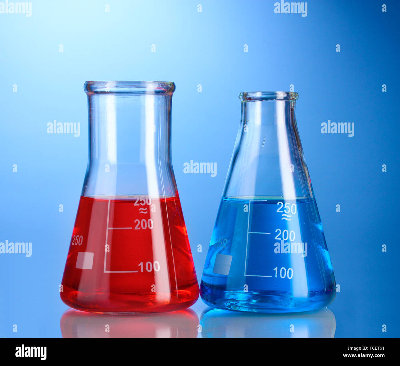 Two flasks with red and blue liquid with reflection on blue background ...