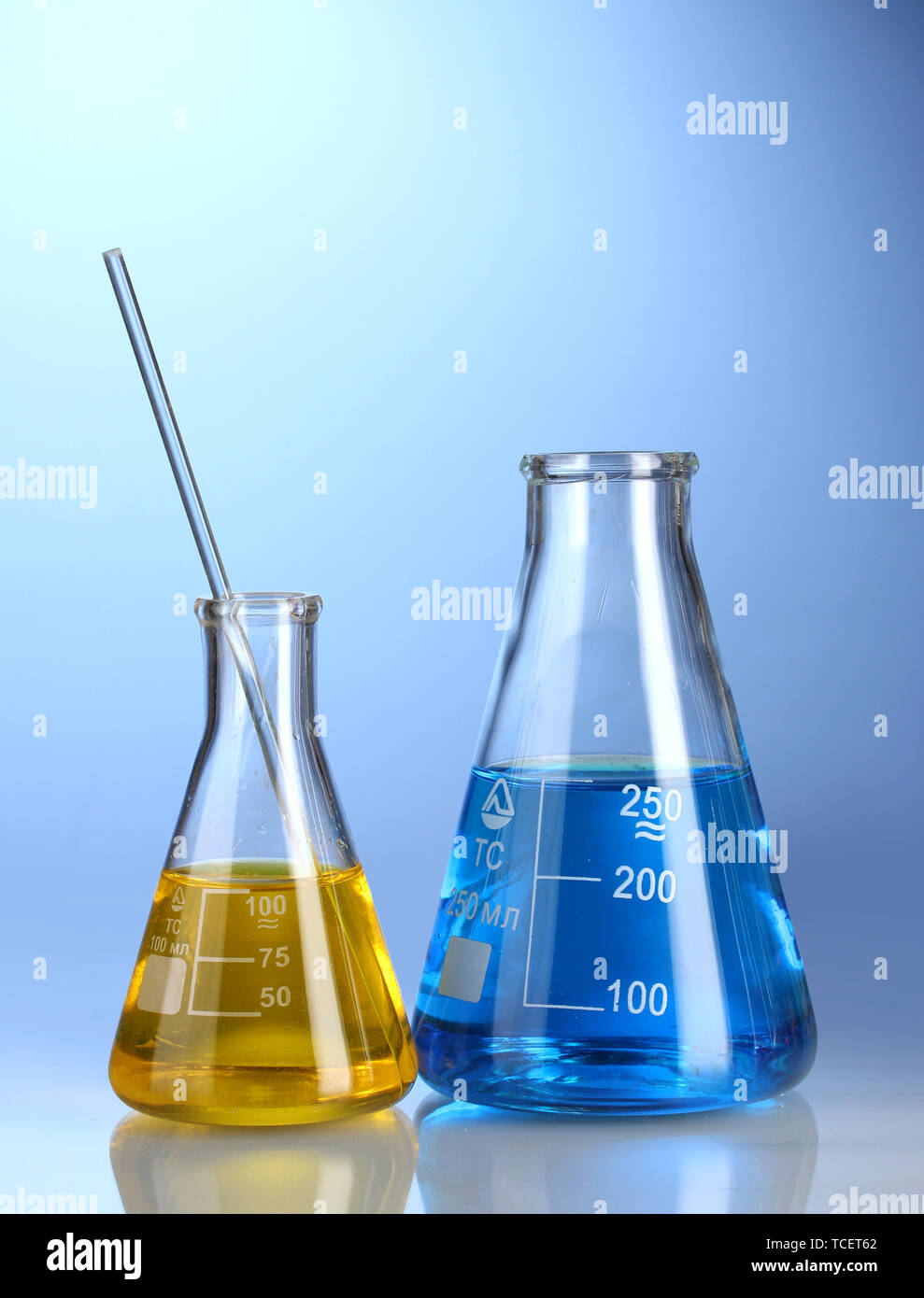 Two flasks with yellow and blue liquid with reflection on blue ...