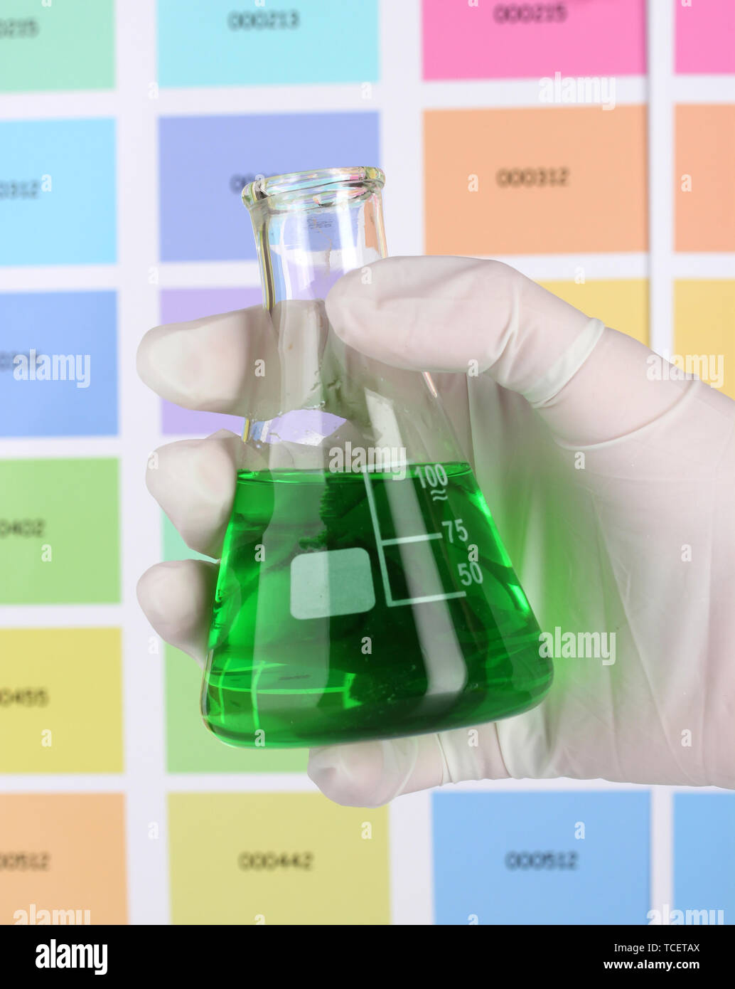 Flask with green liquid in hand on color samples background Stock Photo ...