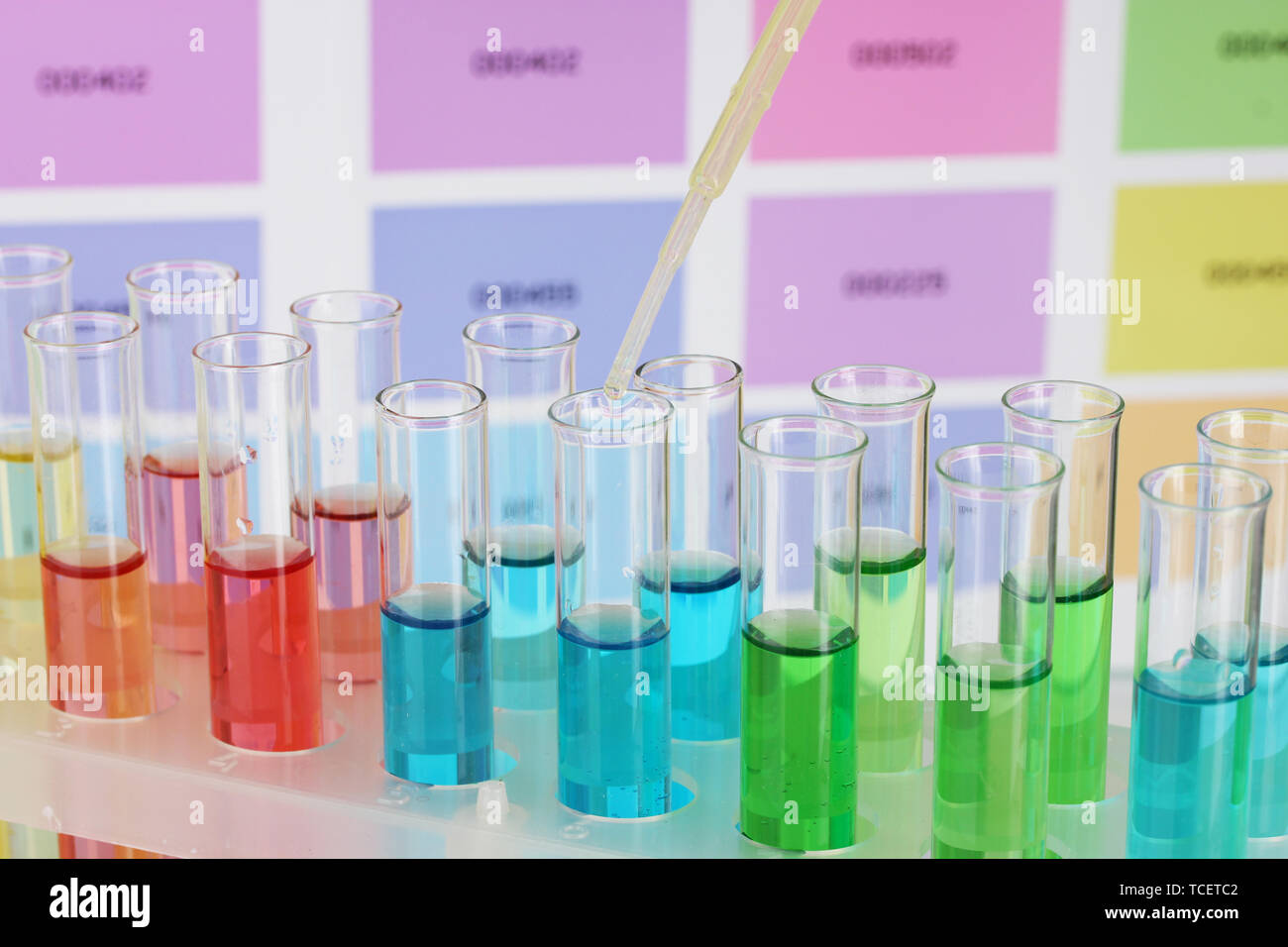 Test-tubes with color liquid and pipette on color samples background ...