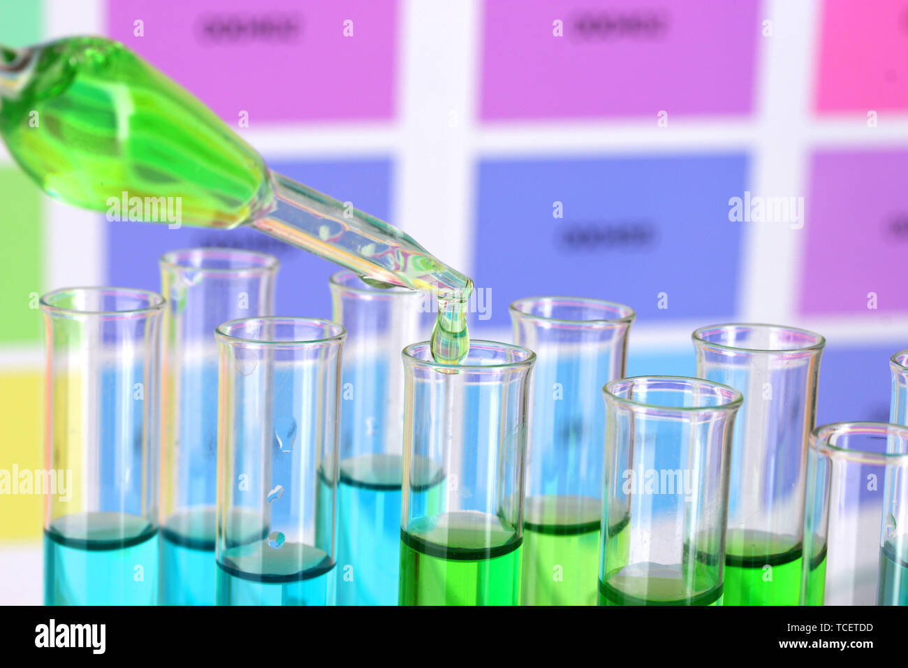 Test-tubes with color liquid and pipette on color samples background ...