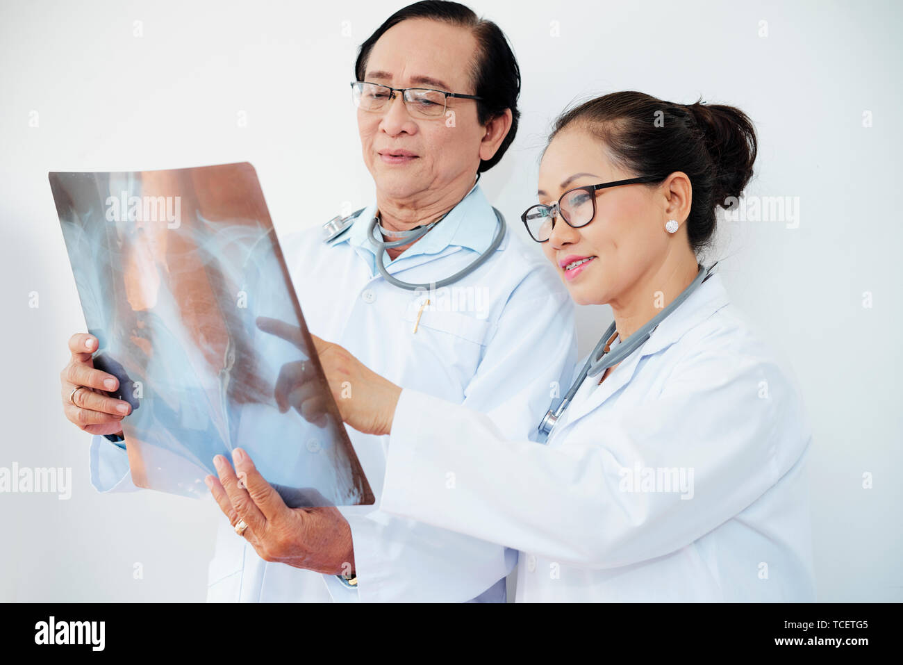 Team of positive Vietnamese doctors discussing chest x-ray of patient ...