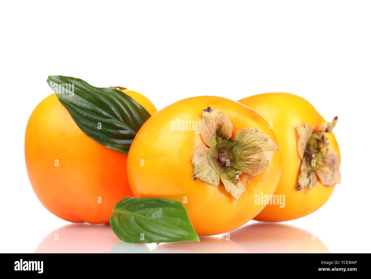 Three appetizing persimmons with green leaves isolated on white Stock ...