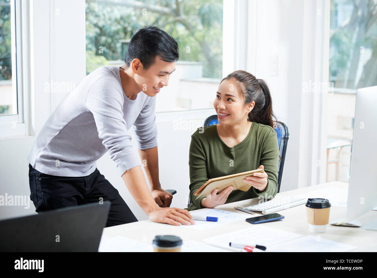 Female UX designer showing her work on tablet computer to smiling ...