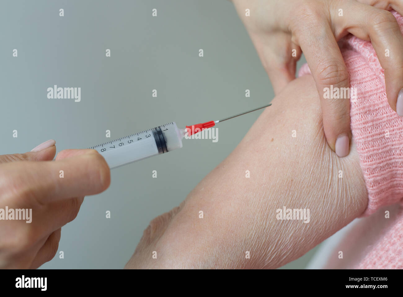 Nurse holding forearm elderly woman injection syringe Stock Photo - Alamy