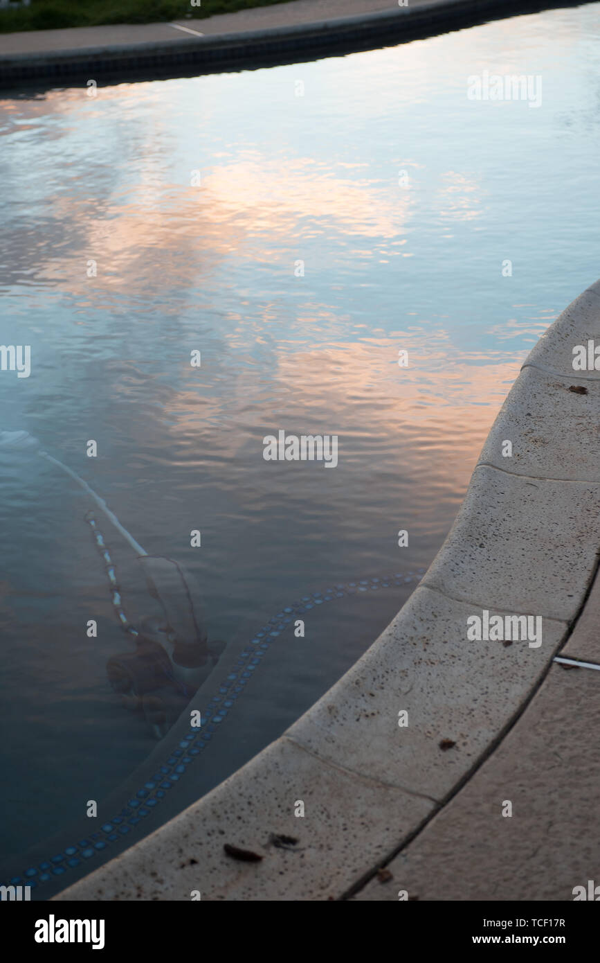 View of tranquil water in pool reflecting evening sky with cleaning ...