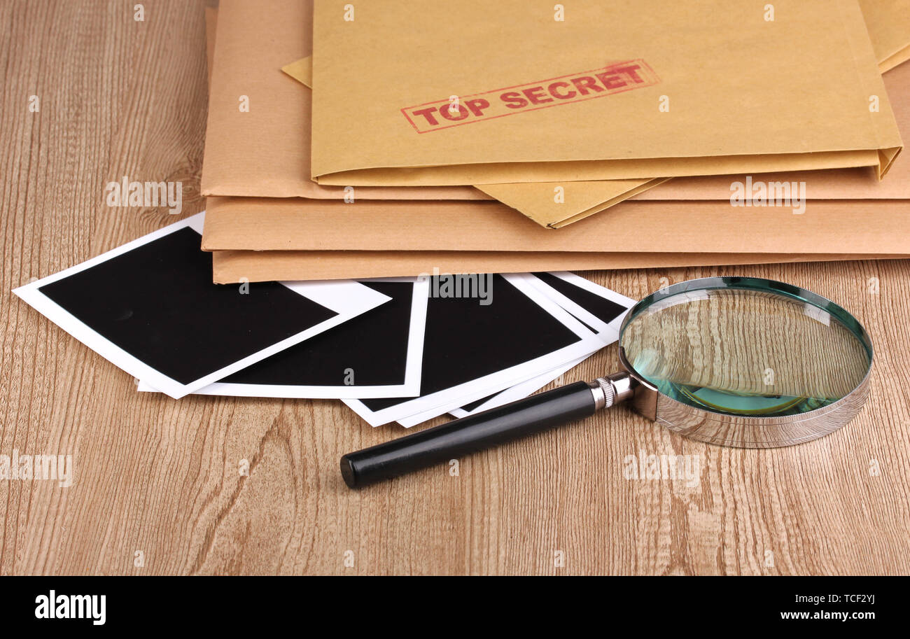 Envelopes with top secret stamp with photo papers and magnifying glass ...