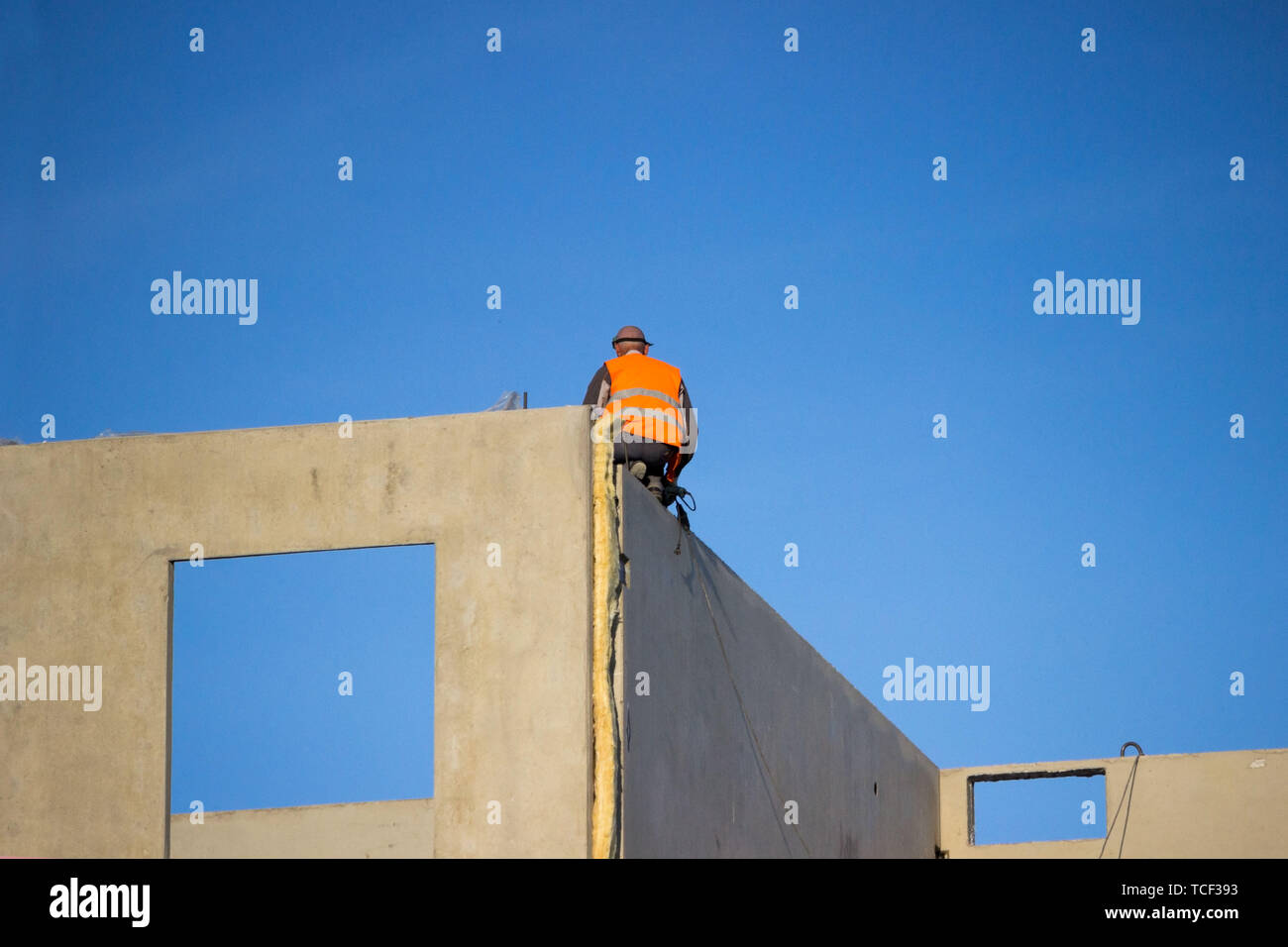 professional construction worker sits on the edge of the wall of a ...