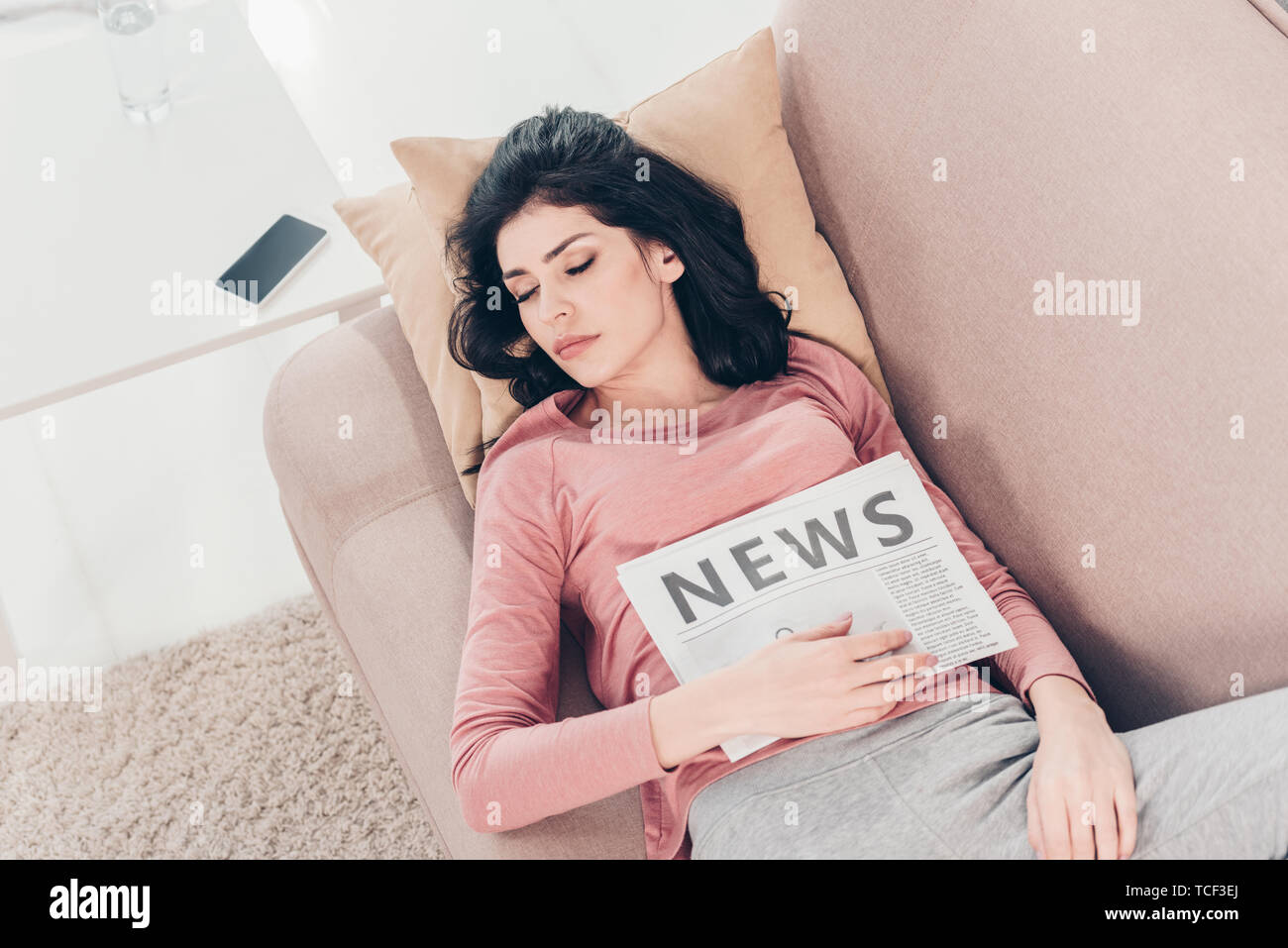 beautiful woman in casual clothes with newspaper sleeping on couch at ...